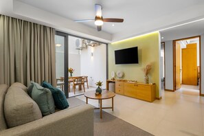 Uma sala de estar moderna com um sofá, uma mesa de jantar e uma TV fixada na parede.