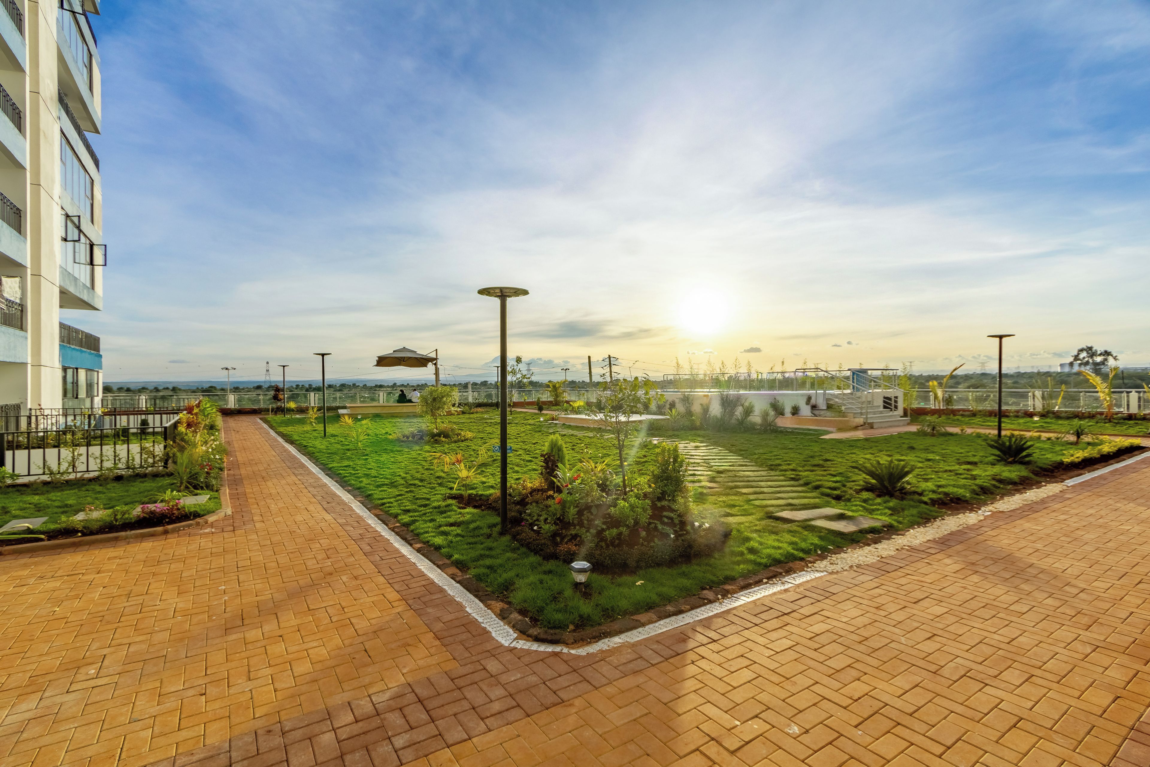 Uma área de jardim ajardinado com caminhos, bancos e postes de luz.