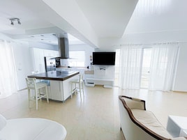 Cozinha moderna com ilha central, armários brancos e fogão embutido.