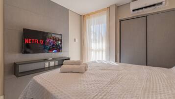 Quarto de hotel com cama, televisão na parede, guarda-roupa e ar condicionado.