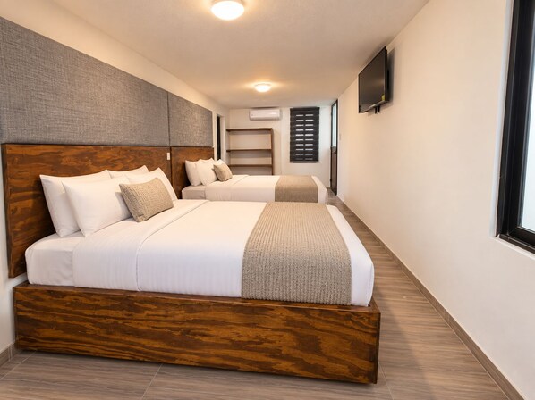 Quarto de hotel com uma cama grande, televisão na parede e janela com persianas.