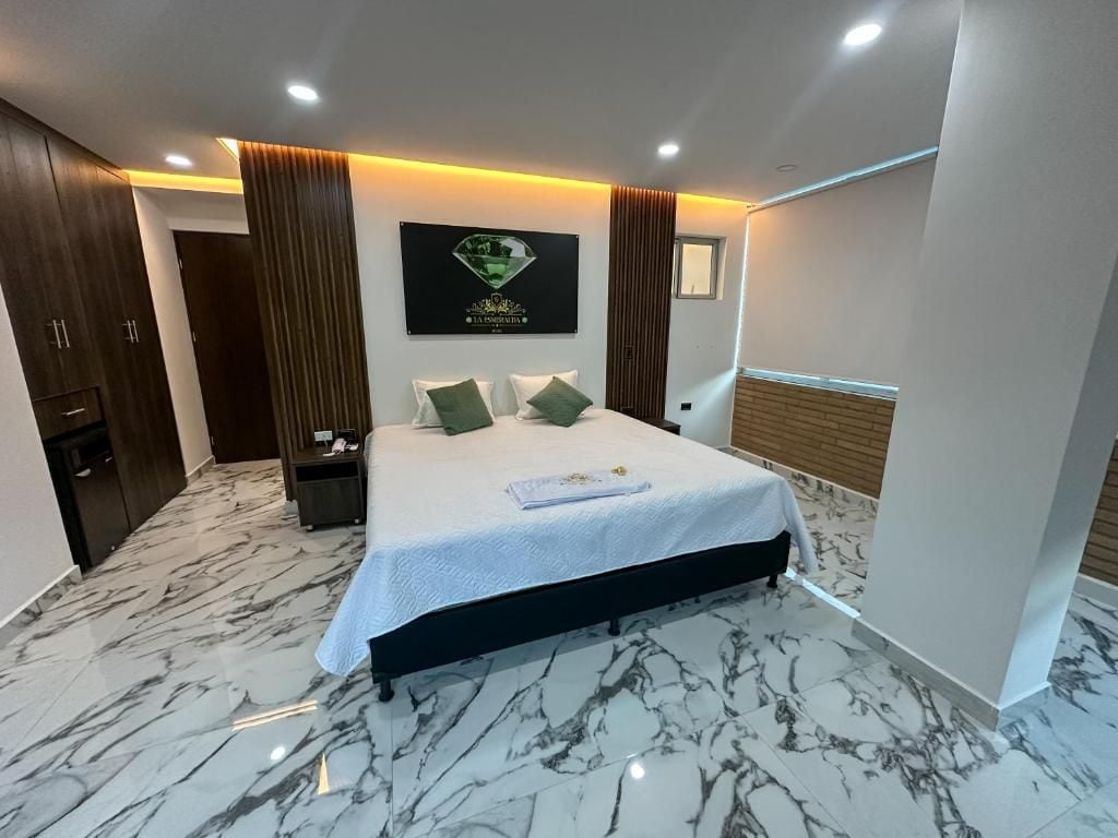 Quarto moderno com piso de mármore, cama com roupa de cama branca e uma obra de arte na parede.