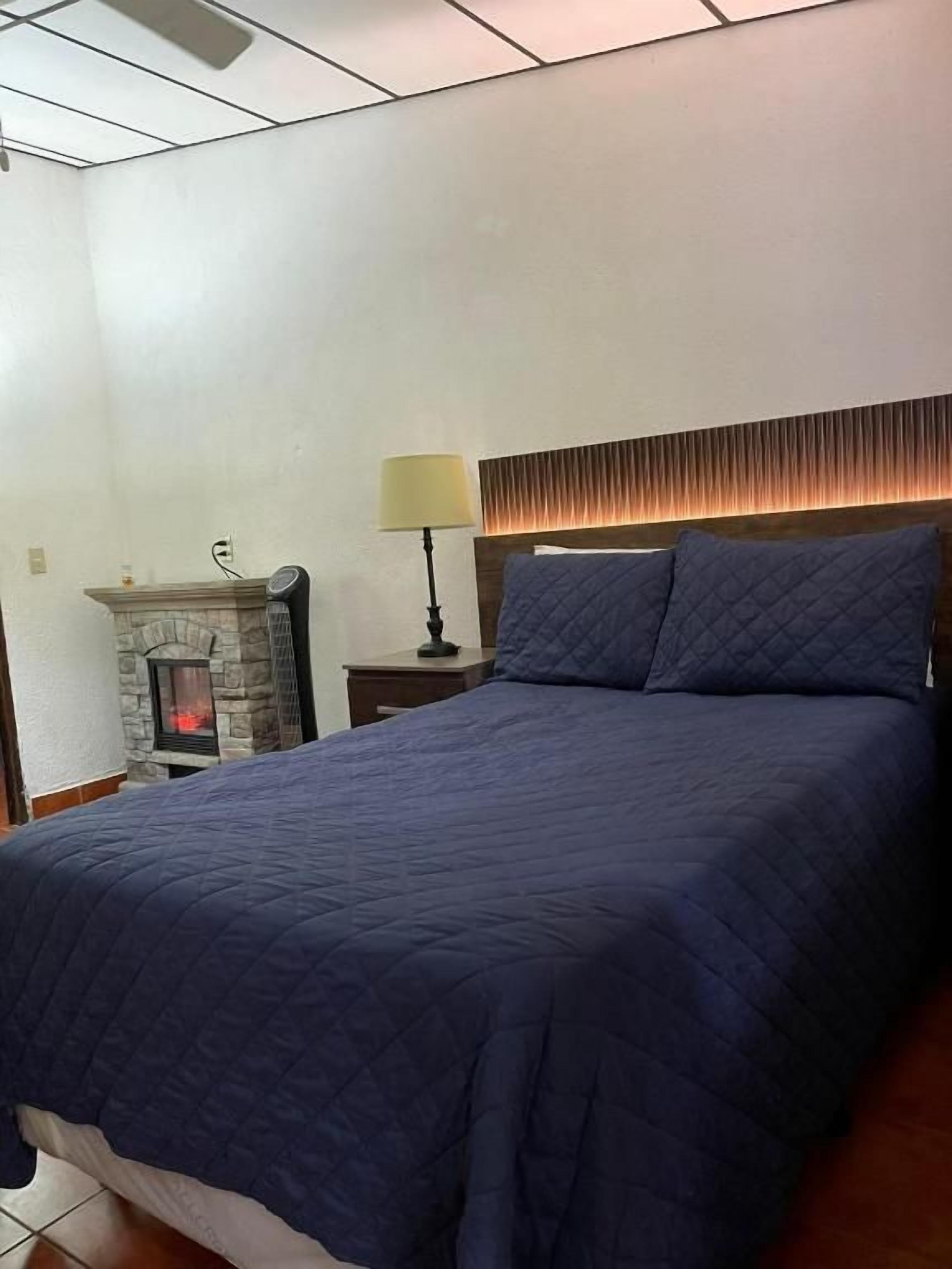 Quarto com uma cama grande, mesa de cabeceira, abajur e lareira.