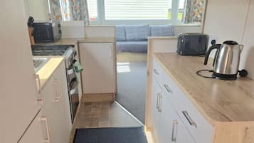 Cozinha compacta com micro-ondas, torradeira, chaleira e uma pequena área de refeições com sofá.