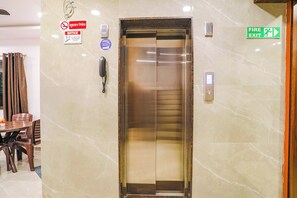 Um elevador com um sinal de saída de incêndio, uma placa de aviso e um sinal de proibido fumar.