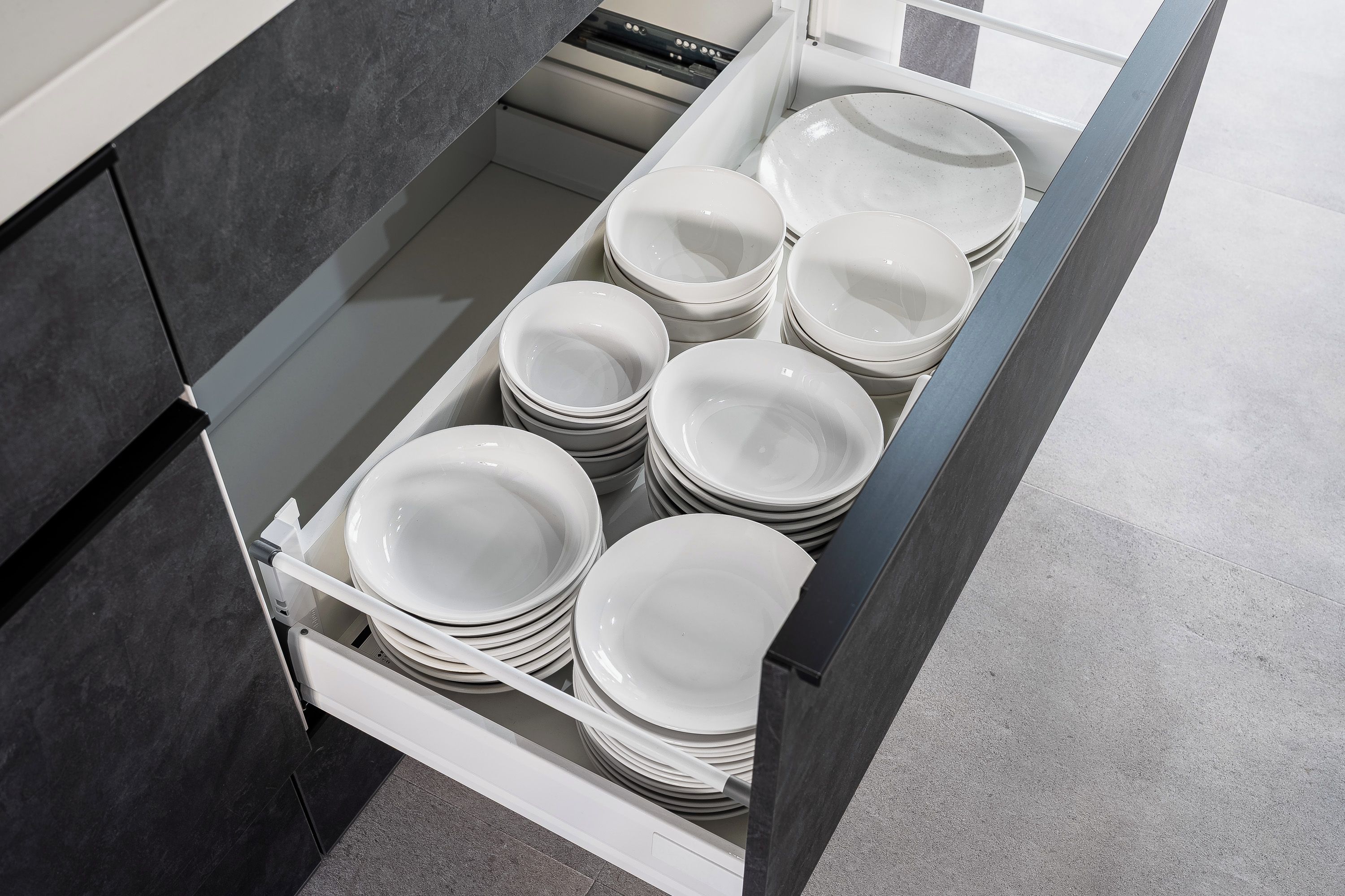 Uma gaveta de cozinha com pratos brancos empilhados de forma organizada.