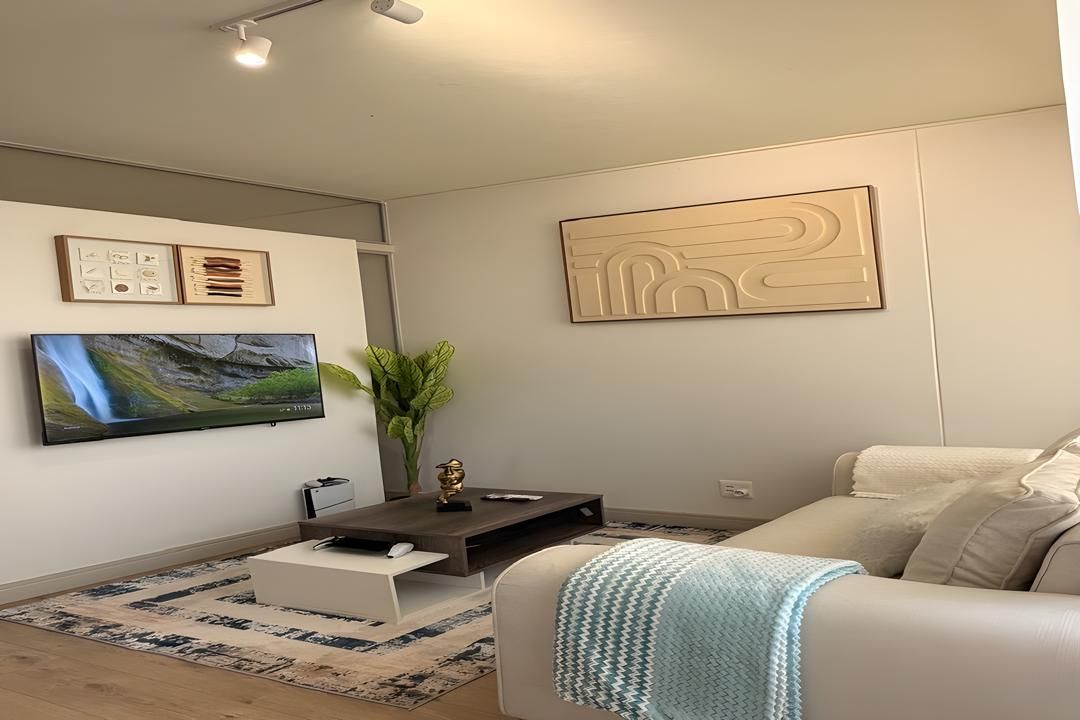 Uma sala de estar moderna com televisão de tela plana, mesinha de centro, sofá e planta decorativa.