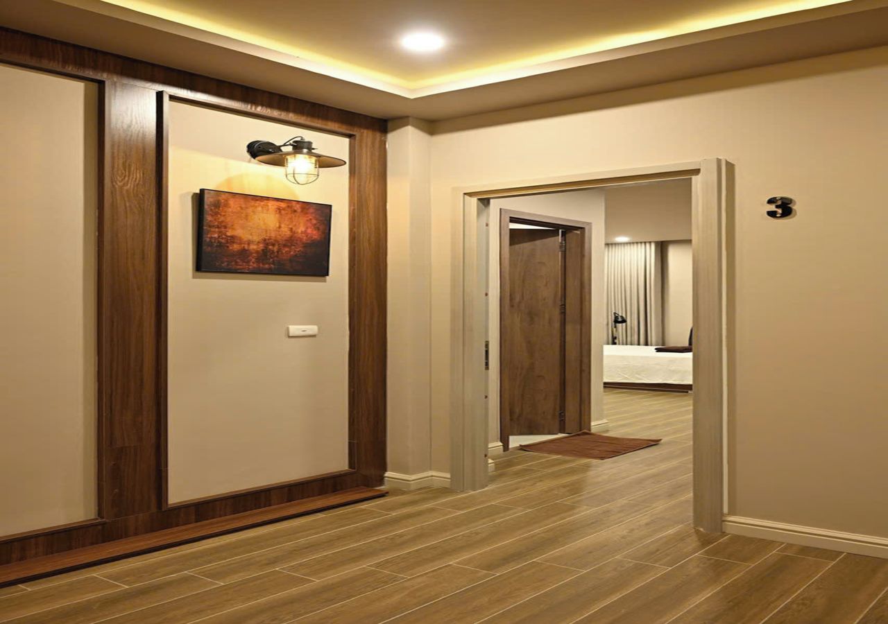 Um corredor com piso de madeira, um quadro na parede e uma porta com o número 3.