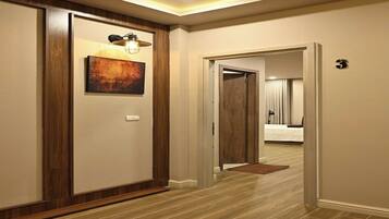 Um corredor com piso de madeira, um quadro na parede e uma porta com o número 3.