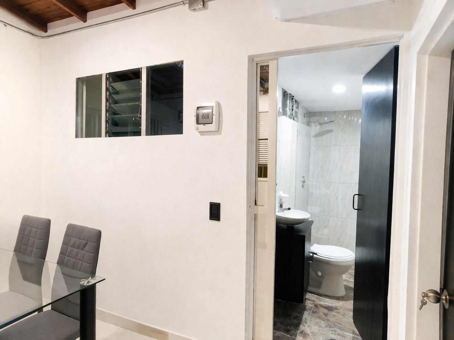 Uma casa de banho moderna com cabine de duche em vidro, sanita e lavatório.