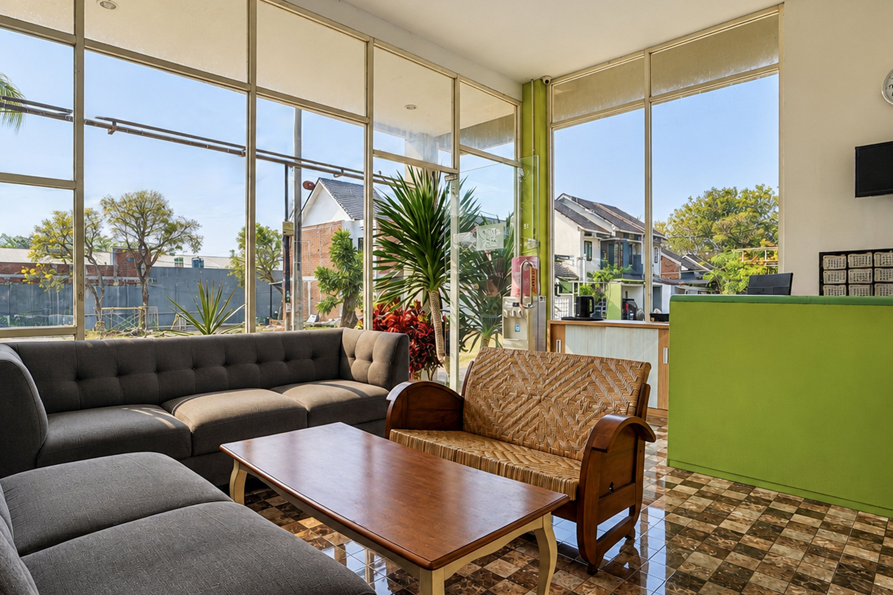 Quarto com sofá, poltrona, mesa de centro, janelas amplas e vista externa.