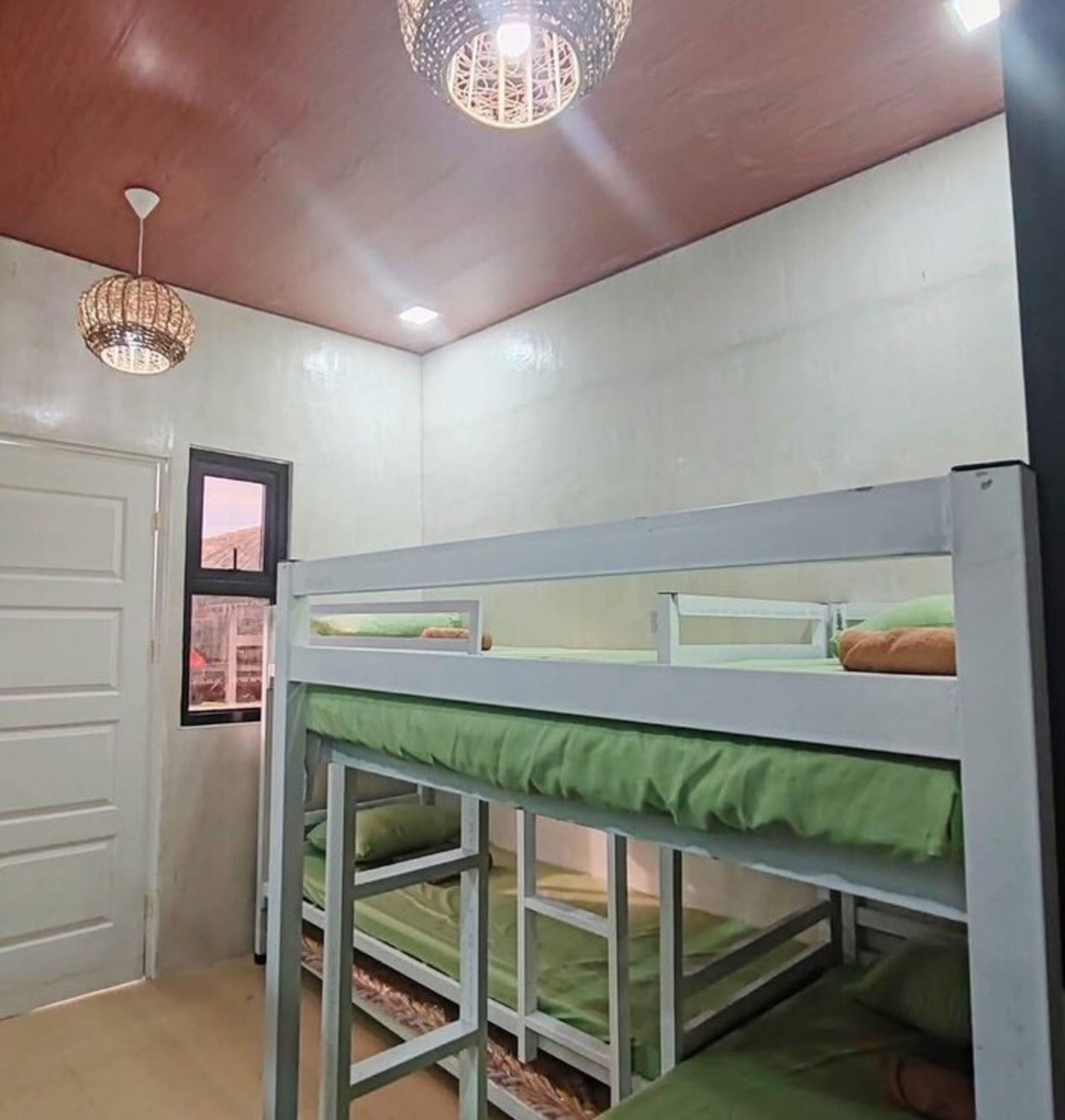 Quarto com beliches, uma porta e um lustre.