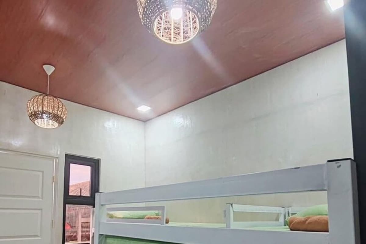 Quarto com beliches, uma porta e um lustre.