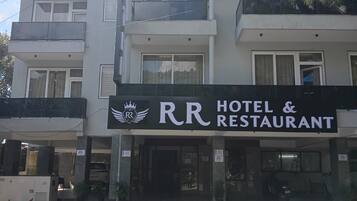 Um hotel com vários andares e uma placa grande com a inscrição 'RR Hotel & Restaurant'.