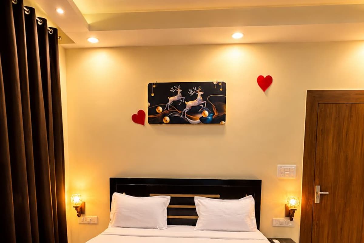 Quarto de hotel com cama, tapete vermelho, obra de arte na parede e ventoinha no teto.