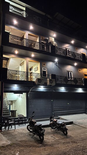 Um edifício com vários andares, varandas, aparelhos de ar condicionado e uma porta de garagem fechada.