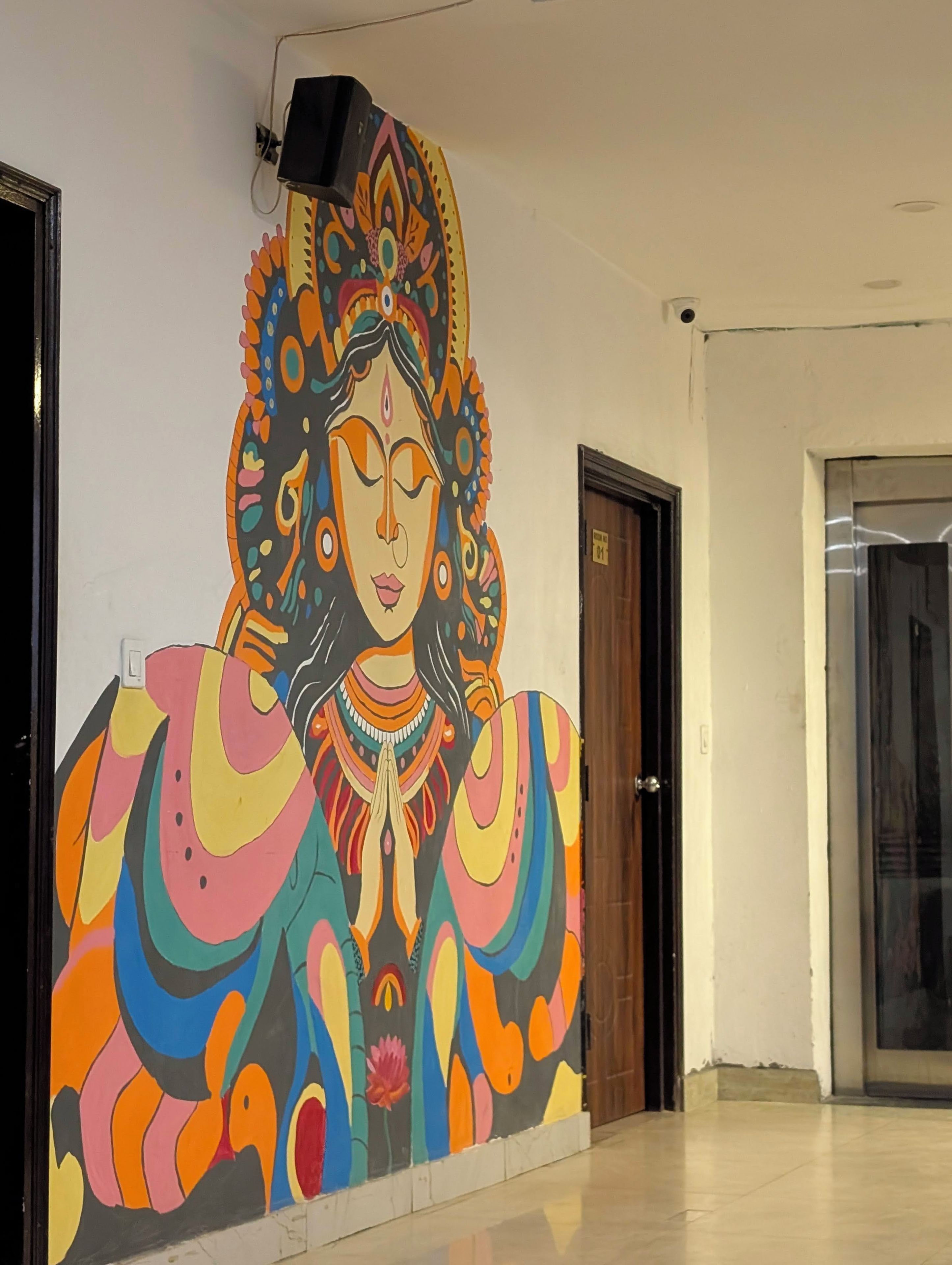 Um mural retrata uma divindade com auréola e vestimentas coloridas em uma parede no corredor.