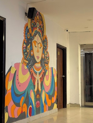 Um mural retrata uma divindade com auréola e vestimentas coloridas em uma parede no corredor.