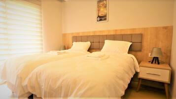 Quarto de hotel com duas camas, uma mesa de cabeceira e um quadro na parede.