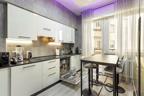 Cozinha moderna com armários brancos, máquina de lavar louça embutida e cafeteira.