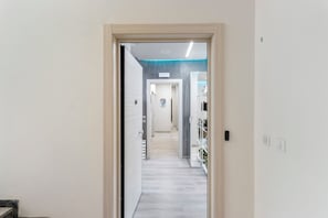 Corredor com porta dando acesso a um quarto com parede branca e detalhe azul.