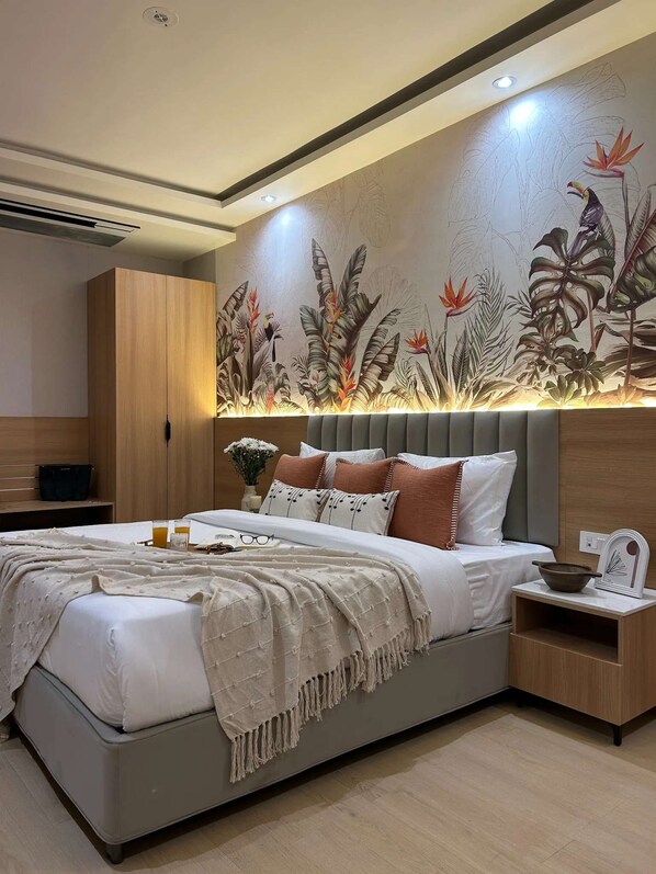 Quarto moderno com cama grande, mesa de cabeceira, guarda-roupa e um mural na parede.