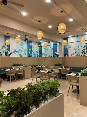 Interior moderno de restaurante com várias mesas, cadeiras e luminárias pendentes de vime.