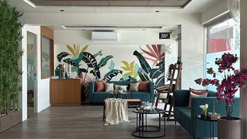 Sala de estar moderna com um grande mural tropical, sofá, mesa de centro e planta em vaso.