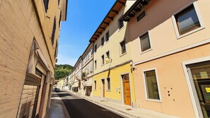 Uma rua estreita ladeada por edifícios altos, alguns com varandas e janelas, sob um céu claro.