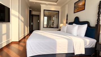 Quarto de hotel com uma cama grande, televisão de tela plana na parede e um quadro sobre a cama.
