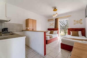 Quarto de hotel compacto com cozinha compacta, duas camas, um pequeno espaço de refeições e vista para o exterior.