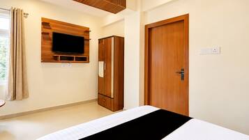 Quarto com cama, guarda-roupa, televisão na parede e porta.