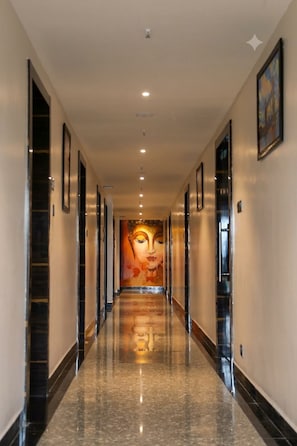 Um corredor com piso espelhado, obras de arte emolduradas nas paredes e um mural central.