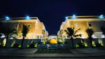 Um hotel moderno com edifícios de dois andares, um elemento central de água e áreas bem iluminadas.