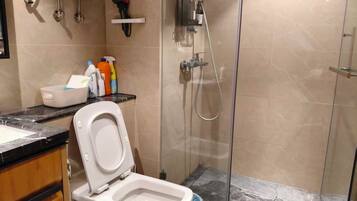 Casa de banho moderna com sanita, chuveiro e vários artigos de higiene pessoal.