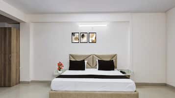 Quarto com cama, mesa de cabeceira e criado-mudo com um telefone.