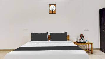 Quarto de hotel com cama, mesa de cabeceira com abajur e uma obra de arte na parede.