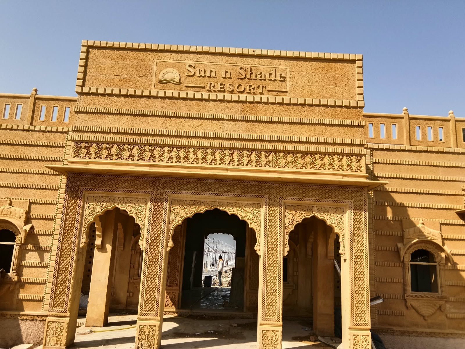 Fachada de edifício com esculturas detalhadas e o nome 'Sun n Shade Resort' em destaque.