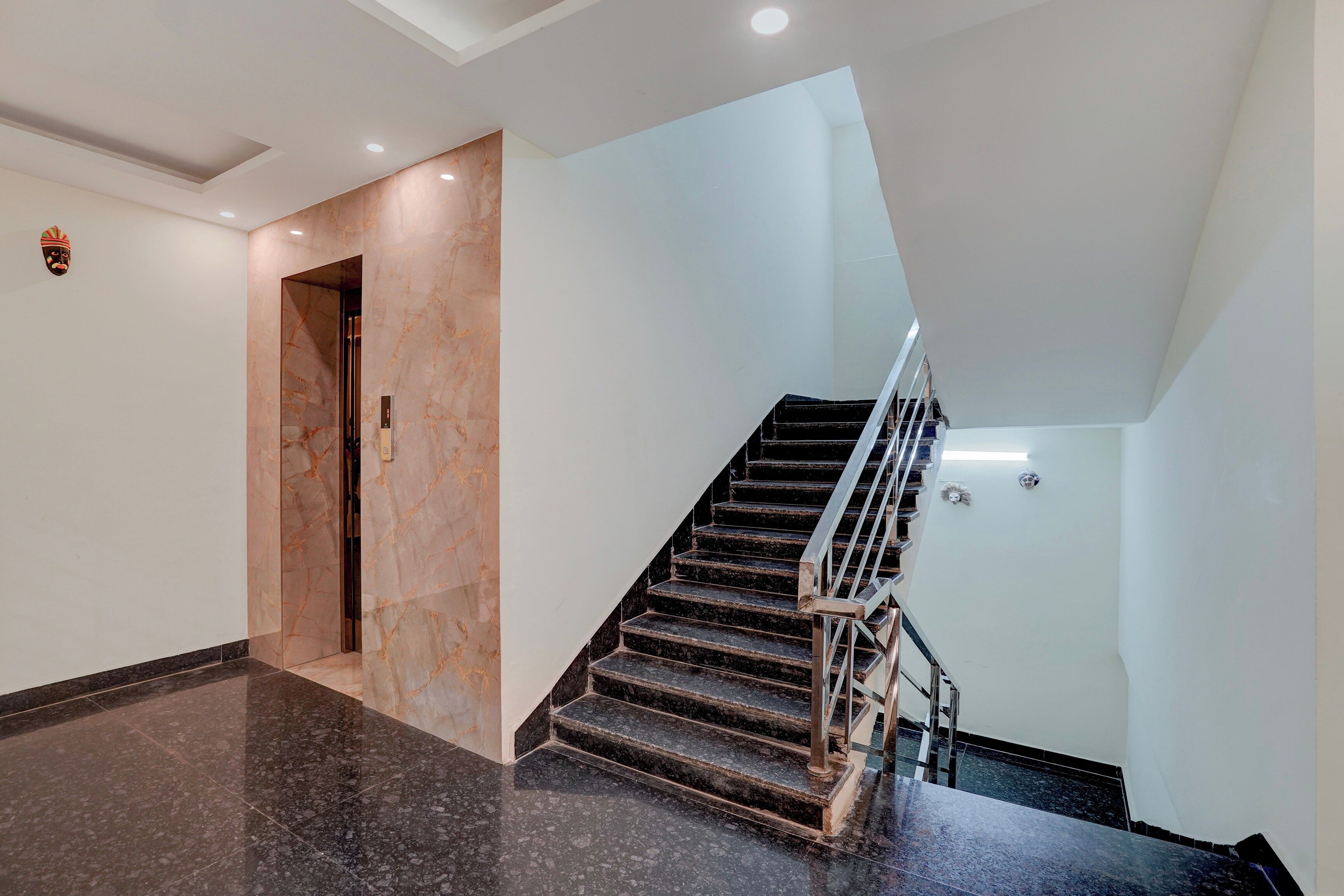 Interior moderno com parede de mármore, escada e porta.