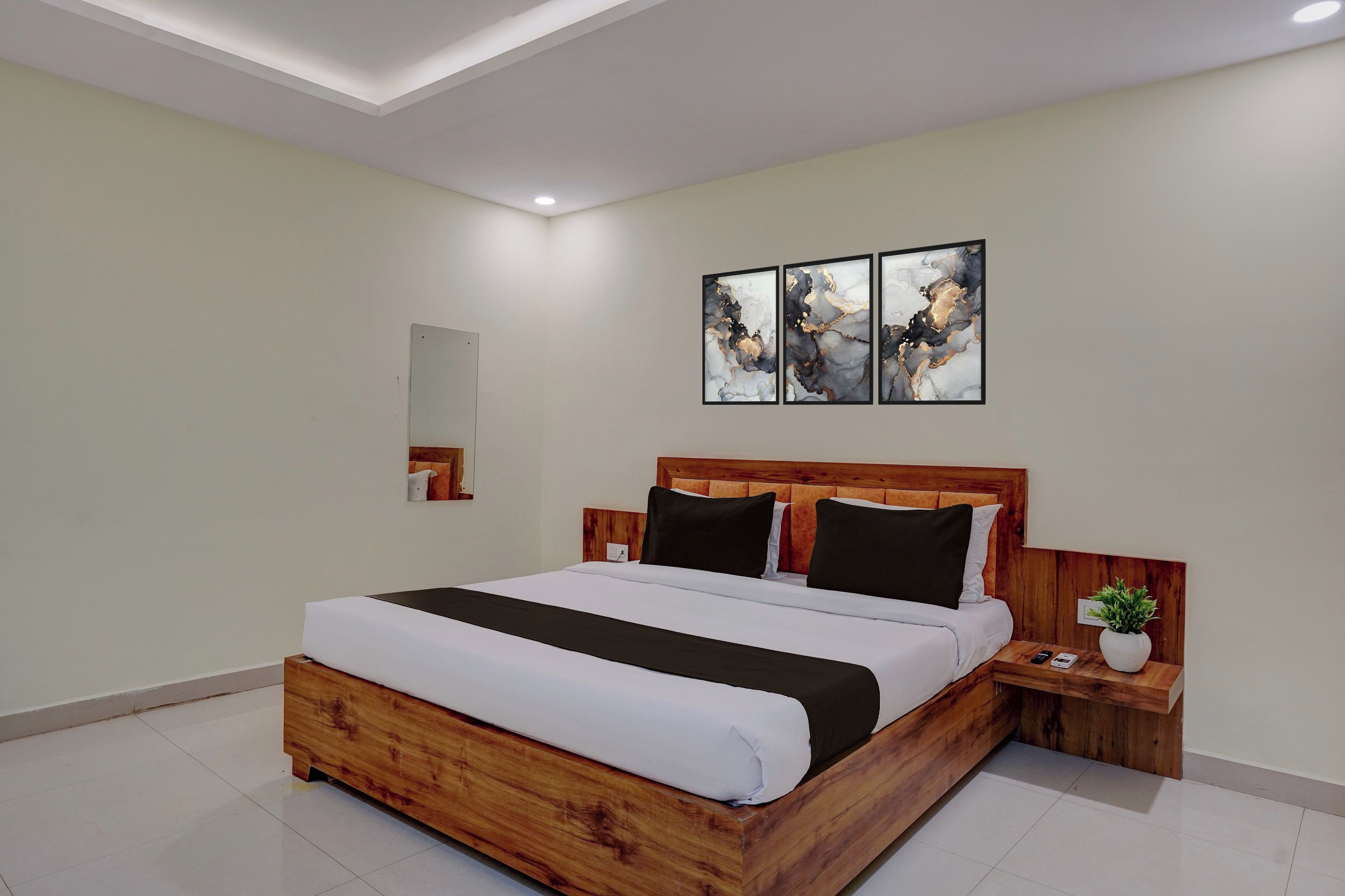 Quarto moderno com cama de madeira, mesa de cabeceira com planta e arte abstrata na parede.