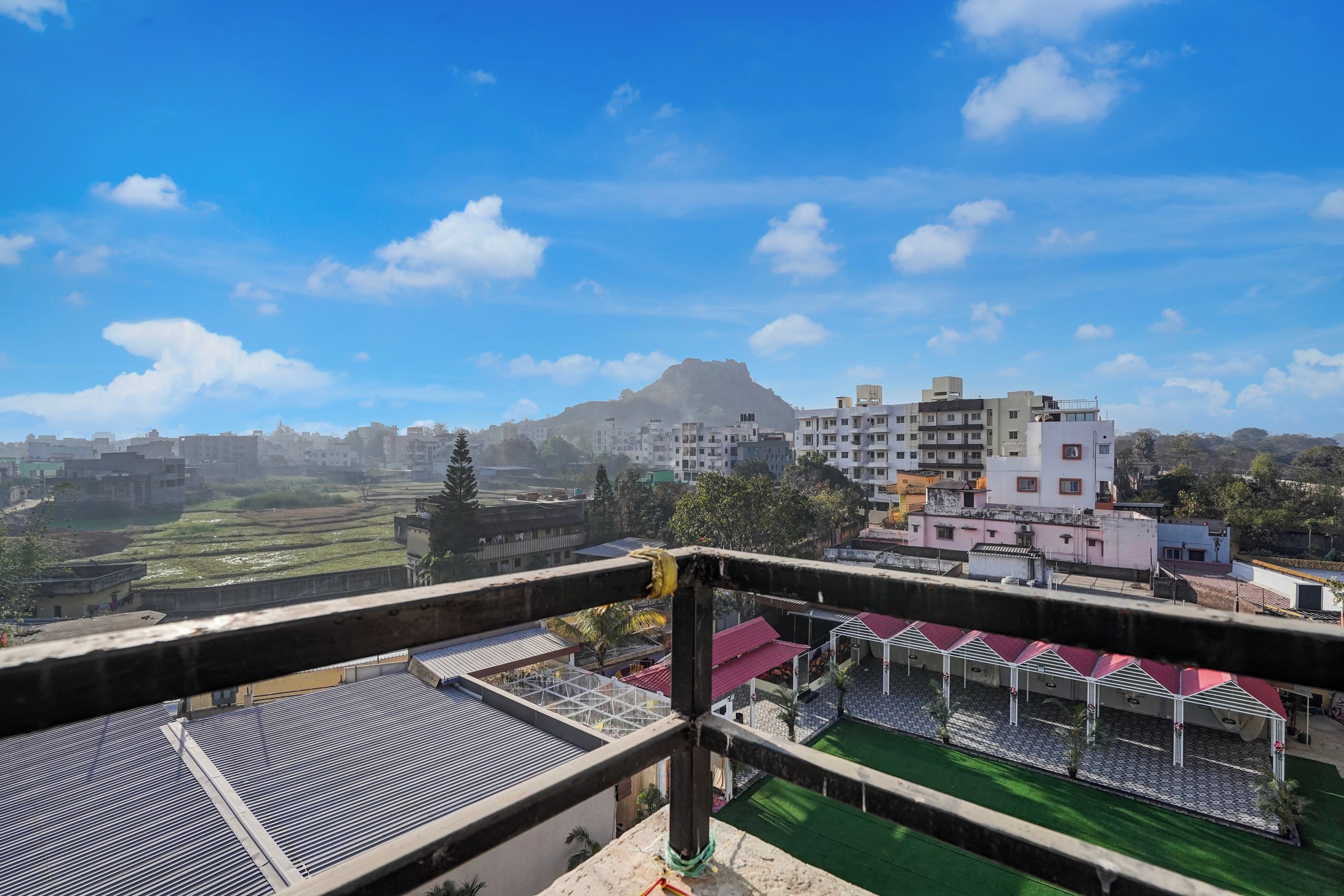 Vista de uma varanda com vista para a paisagem urbana, prédios, uma colina e céu claro.