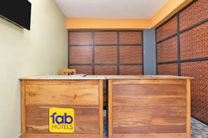 Quarto de hotel com escrivaninha de madeira, uma cadeira e um painel decorativo na parede.