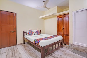 Quarto com cama, armário de madeira e ventilador de teto.