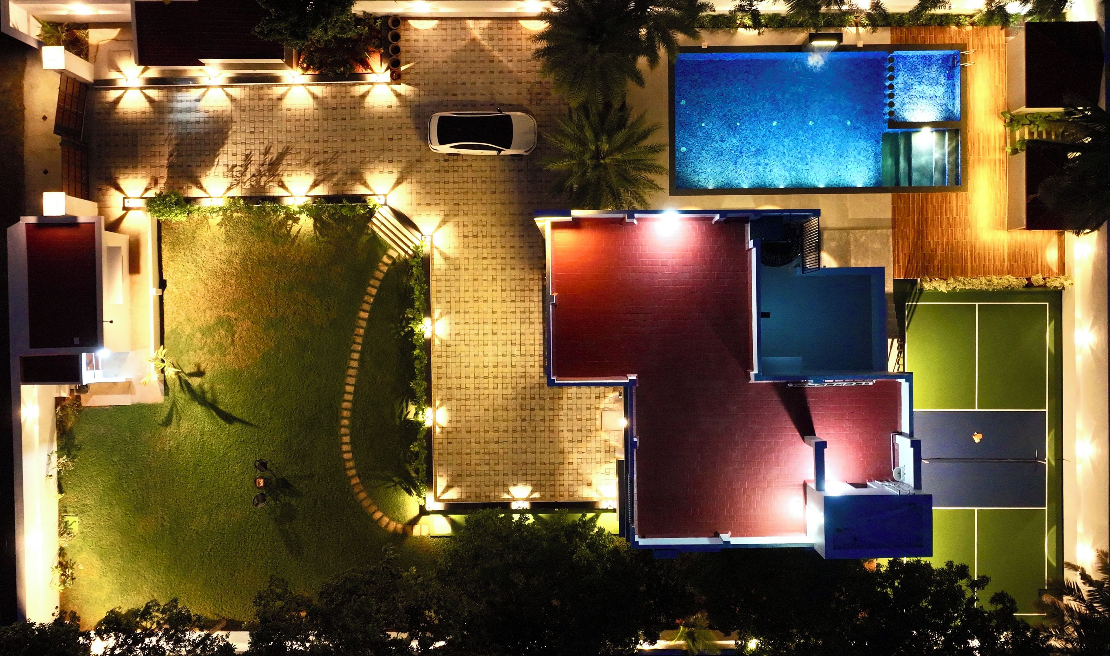 Vista aérea de um hotel com piscina, quadra de tênis e jardins bem cuidados.
