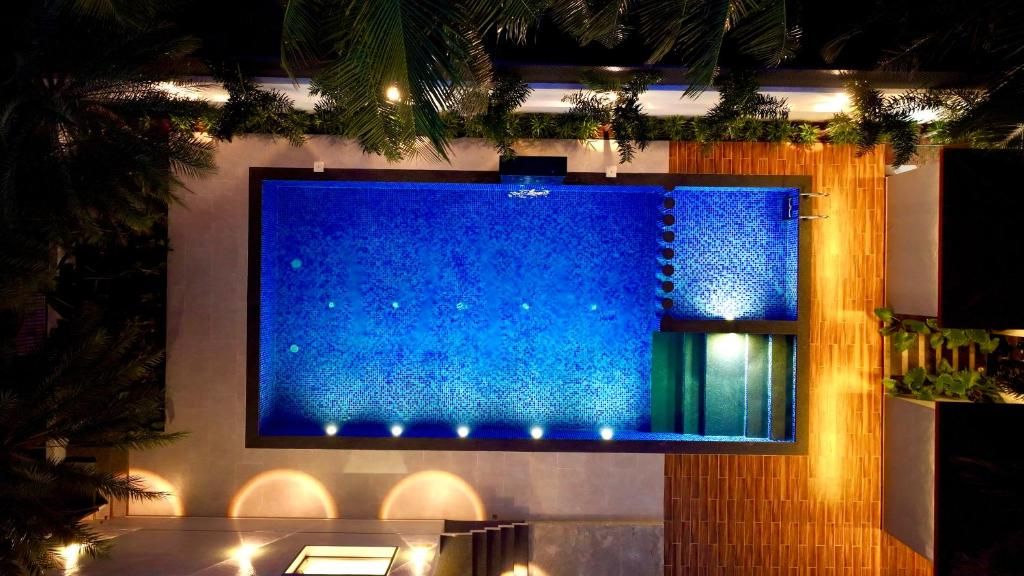 Piscina retangular com revestimento em azulejo, rodeada por um deck de madeira e uma parede com jardim vertical.