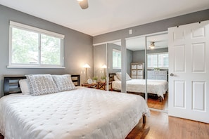 Quarto com cama grande, mesa de cabeceira, abajur e espelho.