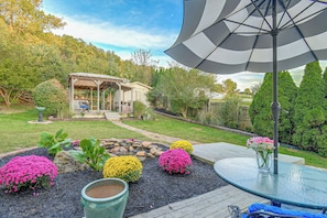 Um jardim com um gazebo, um lago cheio de flores e uma mesa de vidro com guarda-sol.