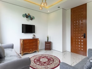 Uma sala de estar moderna com uma TV de tela plana, um armário de madeira, um tapete vermelho estampado e uma porta de madeira grande.