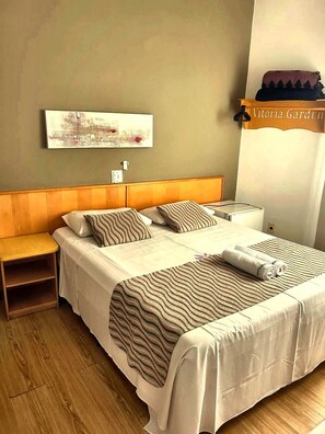 Quarto de hotel com cama, mesa de cabeceira e uma obra de arte na parede.