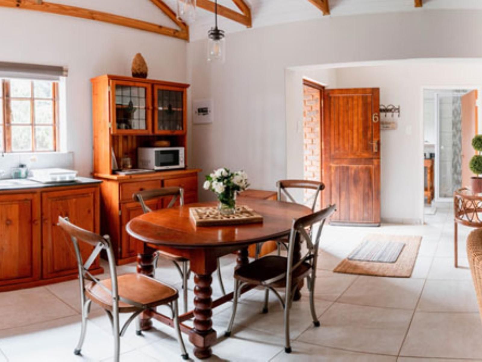 Uma sala de jantar com mesa e cadeiras de madeira, uma cozinha com armários de madeira e uma porta que dá para outro cômodo.
